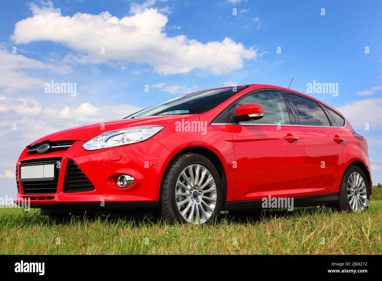 Red car on a blue sky background with white clouds. The car is standing ...