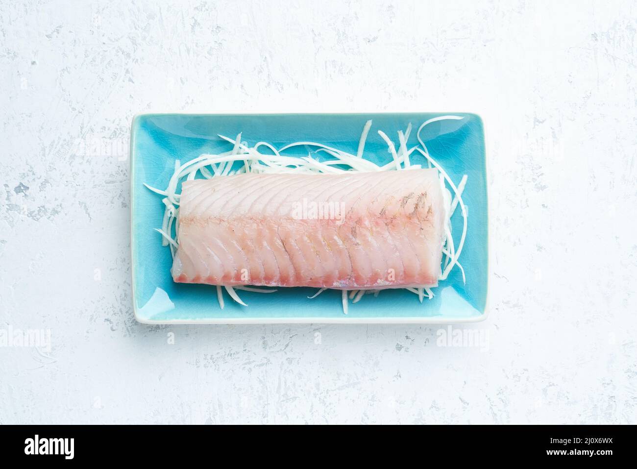 Fillet of raw white walleye fish on a blue plate on a white background ...