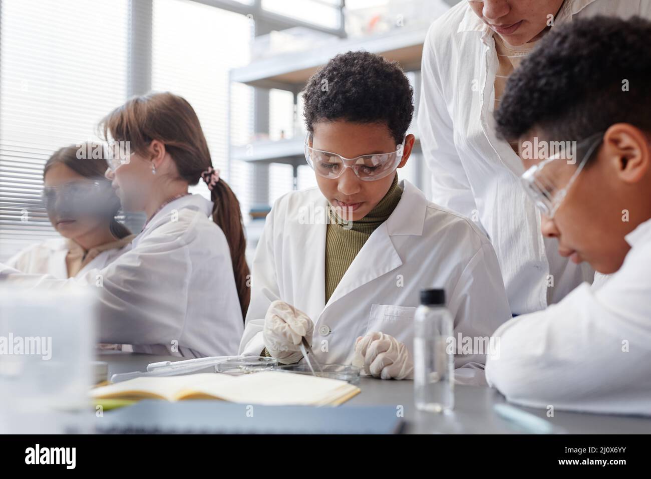 Portrait of young African American girl wearing lab coat in class while ...