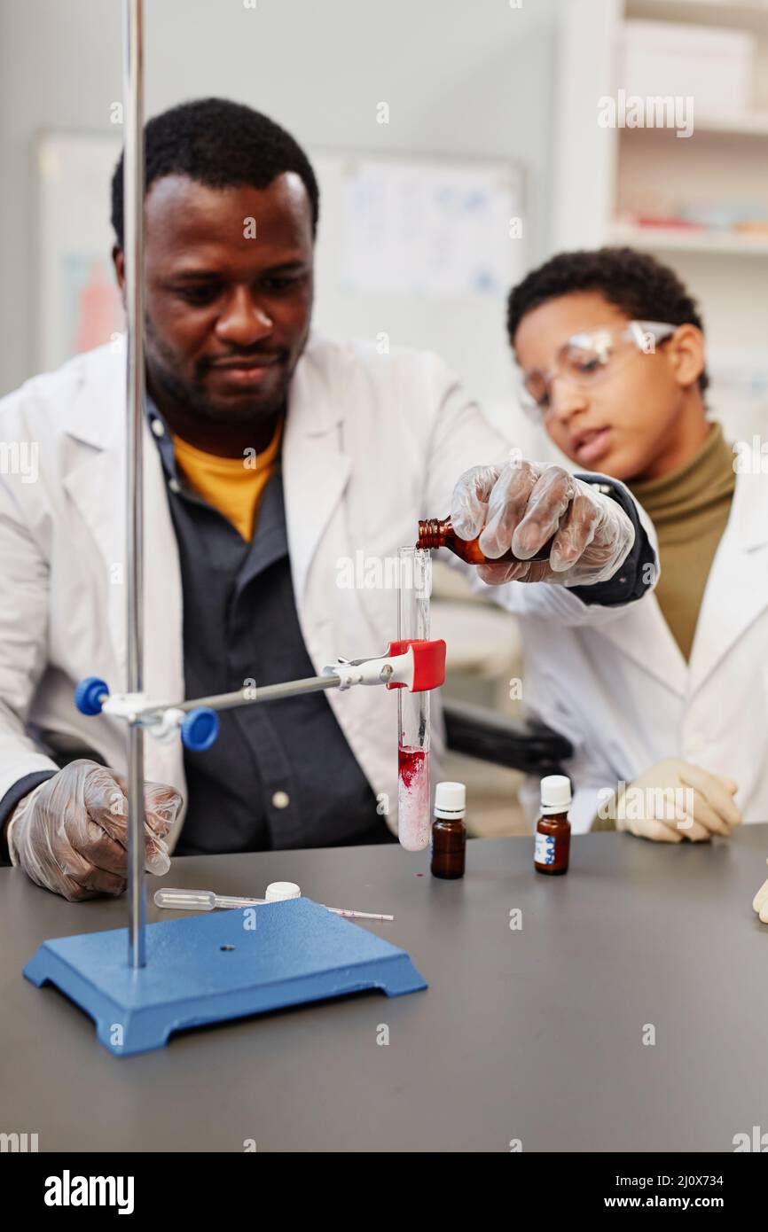 Vertical portrait of African American teacher demonstrating science ...