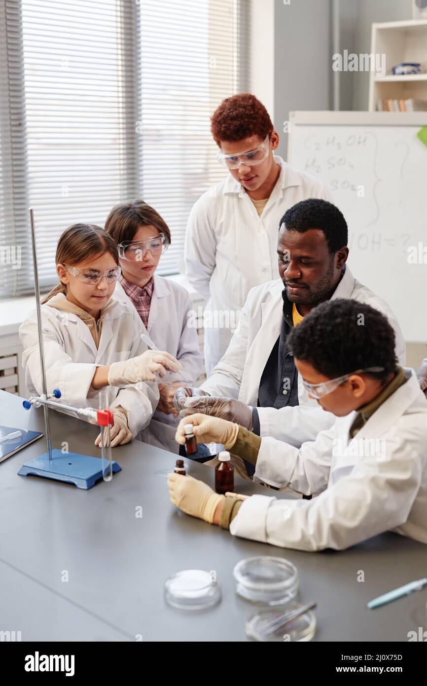 Vertical portrait of African American teacher demonstrating science ...