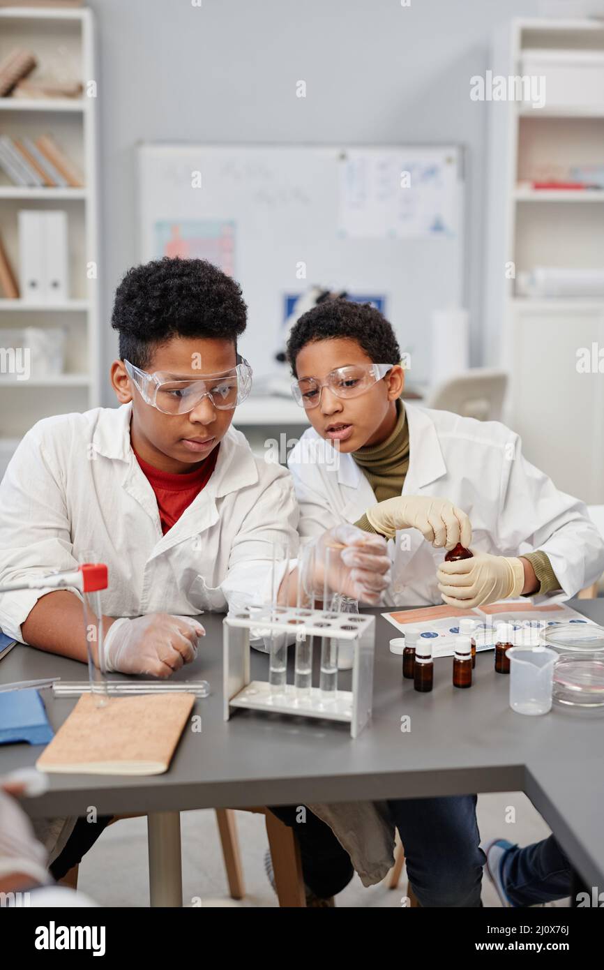 Vertican portrait of two curious African American children watching ...
