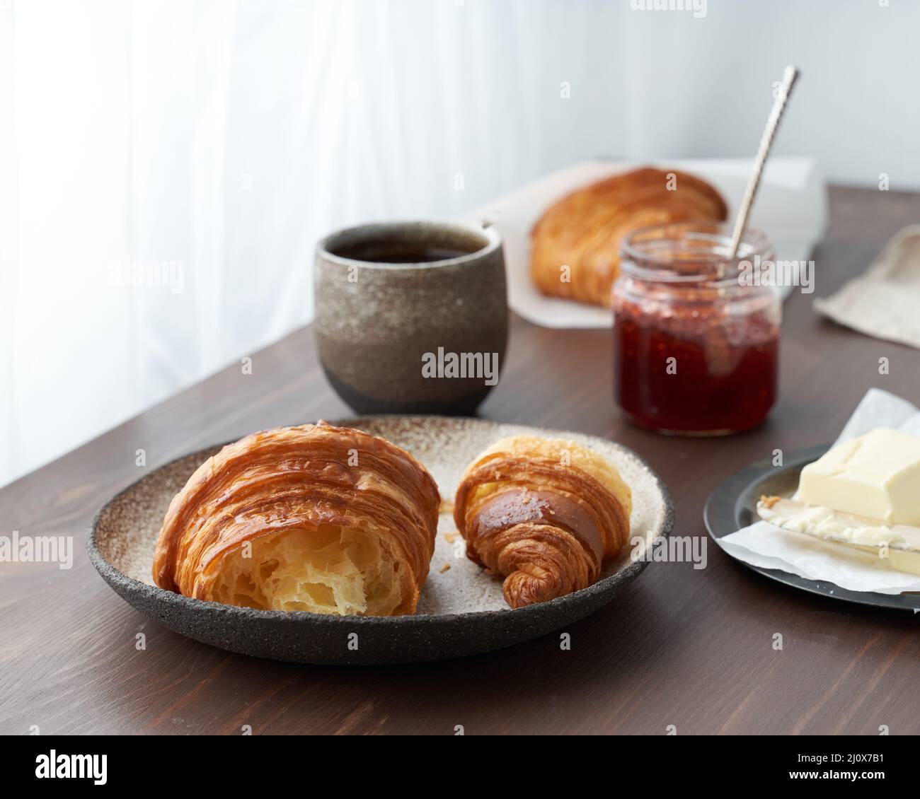Morning breakfast with croissant on plate, cup of coffee, jam and ...