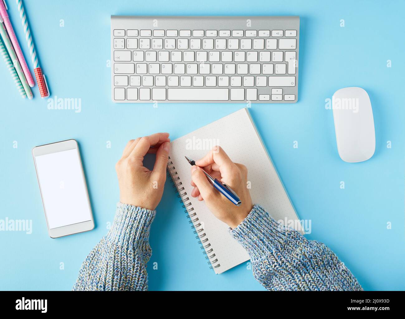 Faceless woman writing in notepad. Mobile phone with blank white screen ...
