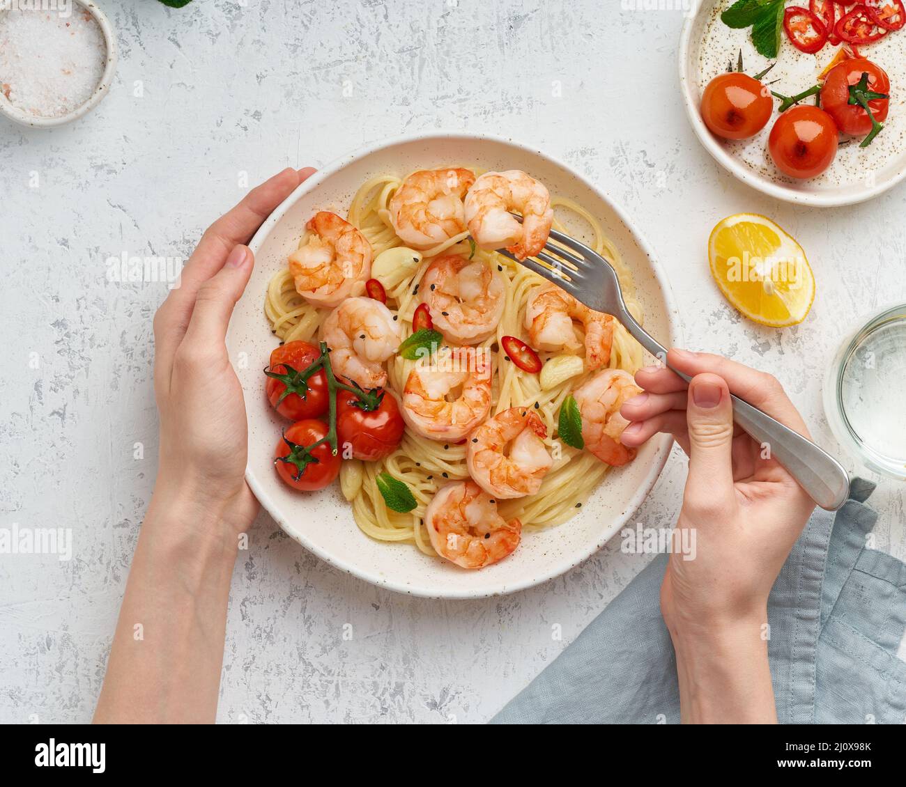Pasta bavette with fried shrimps, bechamel sauce. Woman hands in frame ...