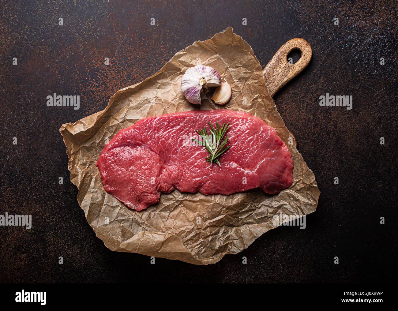 Beef lean raw fillet steak on baking paper with rosemary, garlic and ...