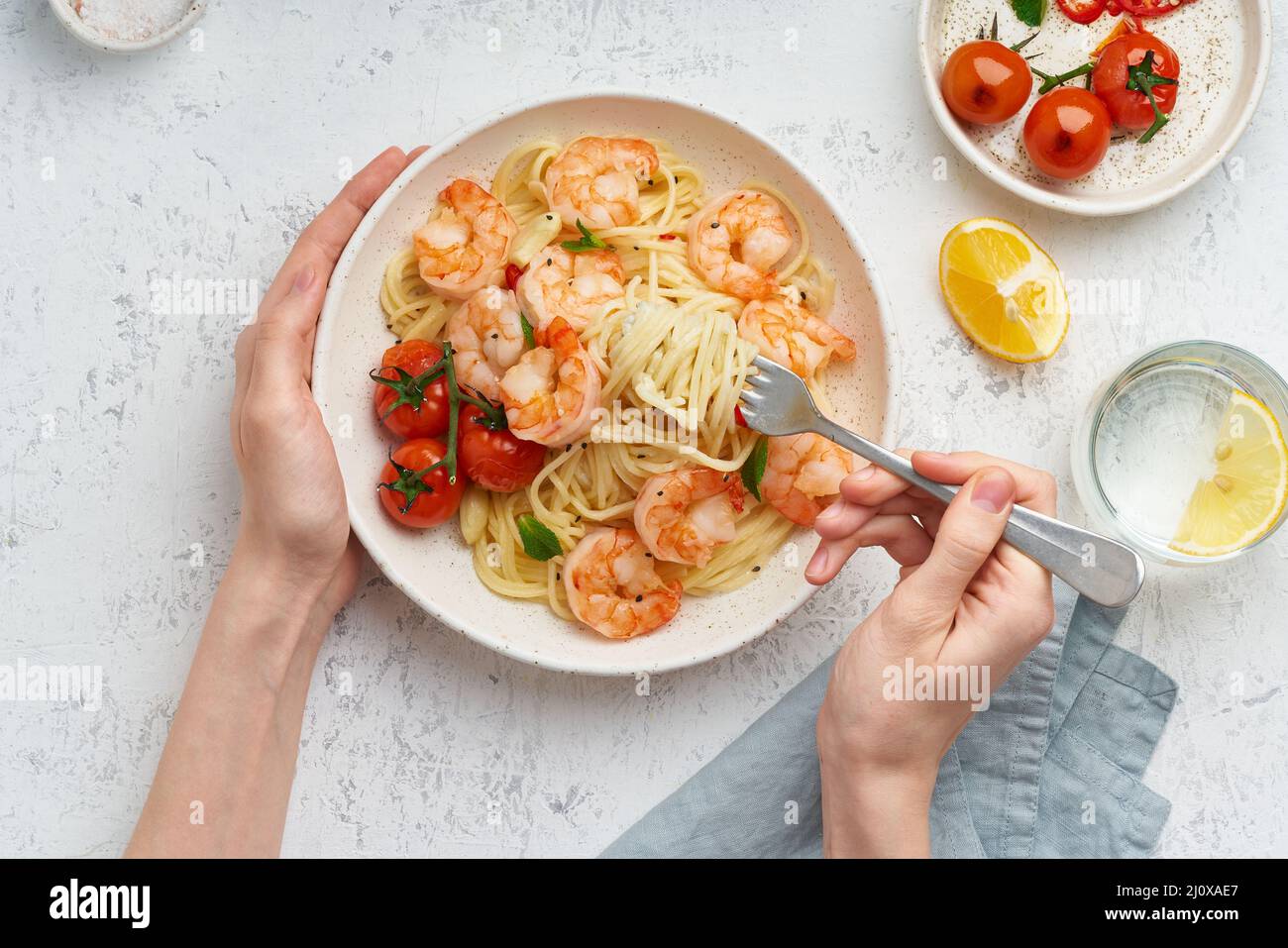 Pasta bavette with fried shrimps, bechamel sauce. Woman hands in frame ...