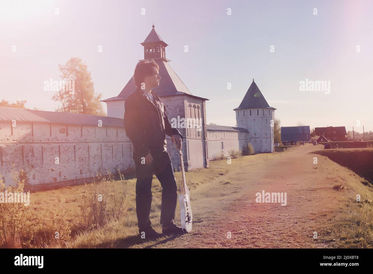 A man with an electric guitar on the railway. A musician in a leather ...