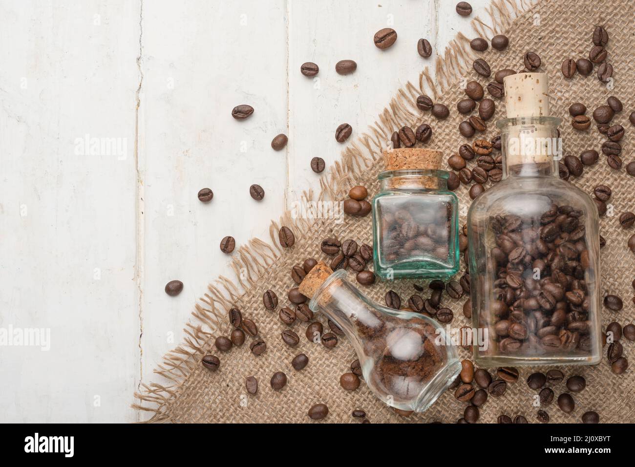 Grains of coffee in a glass jar, on a light wooden texture. With empty ...