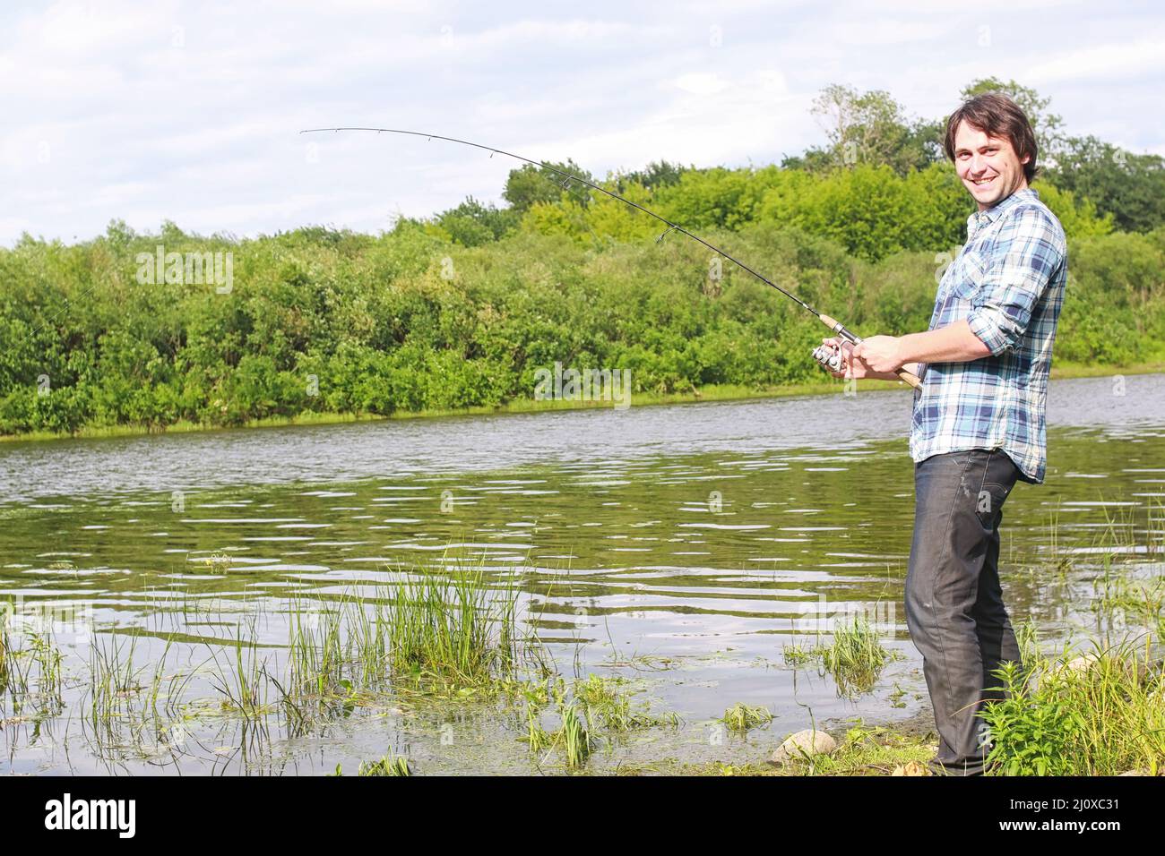 A man with a beard is fishing for spinning in the river Stock Photo - Alamy