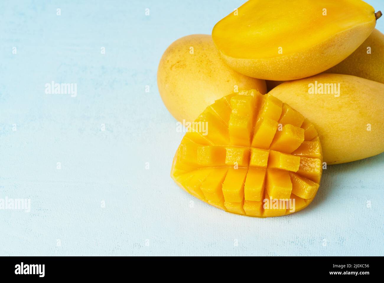 Four whole mango fruits on bright blue table and cut into slices. Large ...