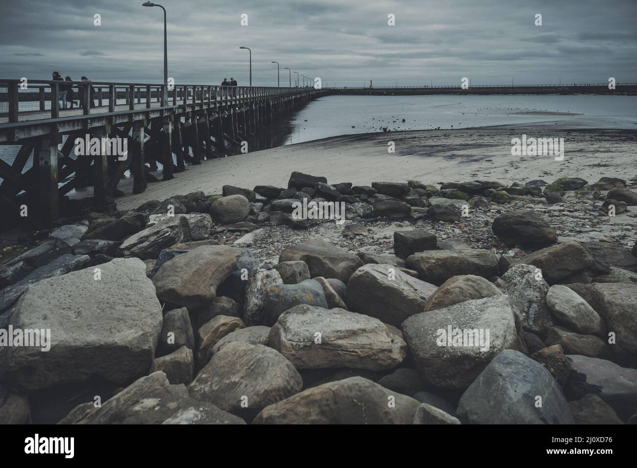 View of Amble pier boardwalk and rocky beach on the Northumberland ...