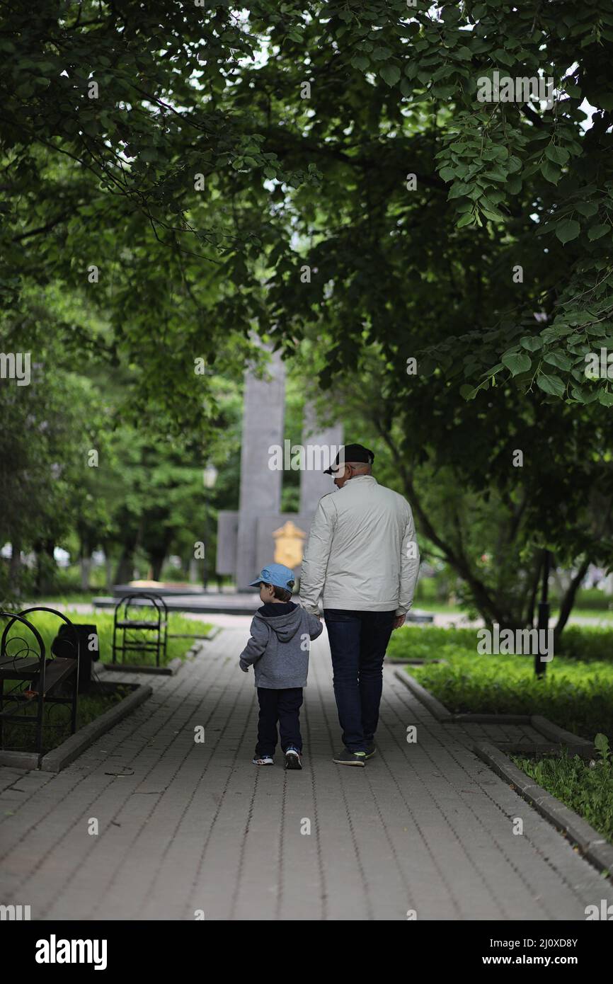 Grandpa is walking with her grandson in a spring park. Grandson and ...