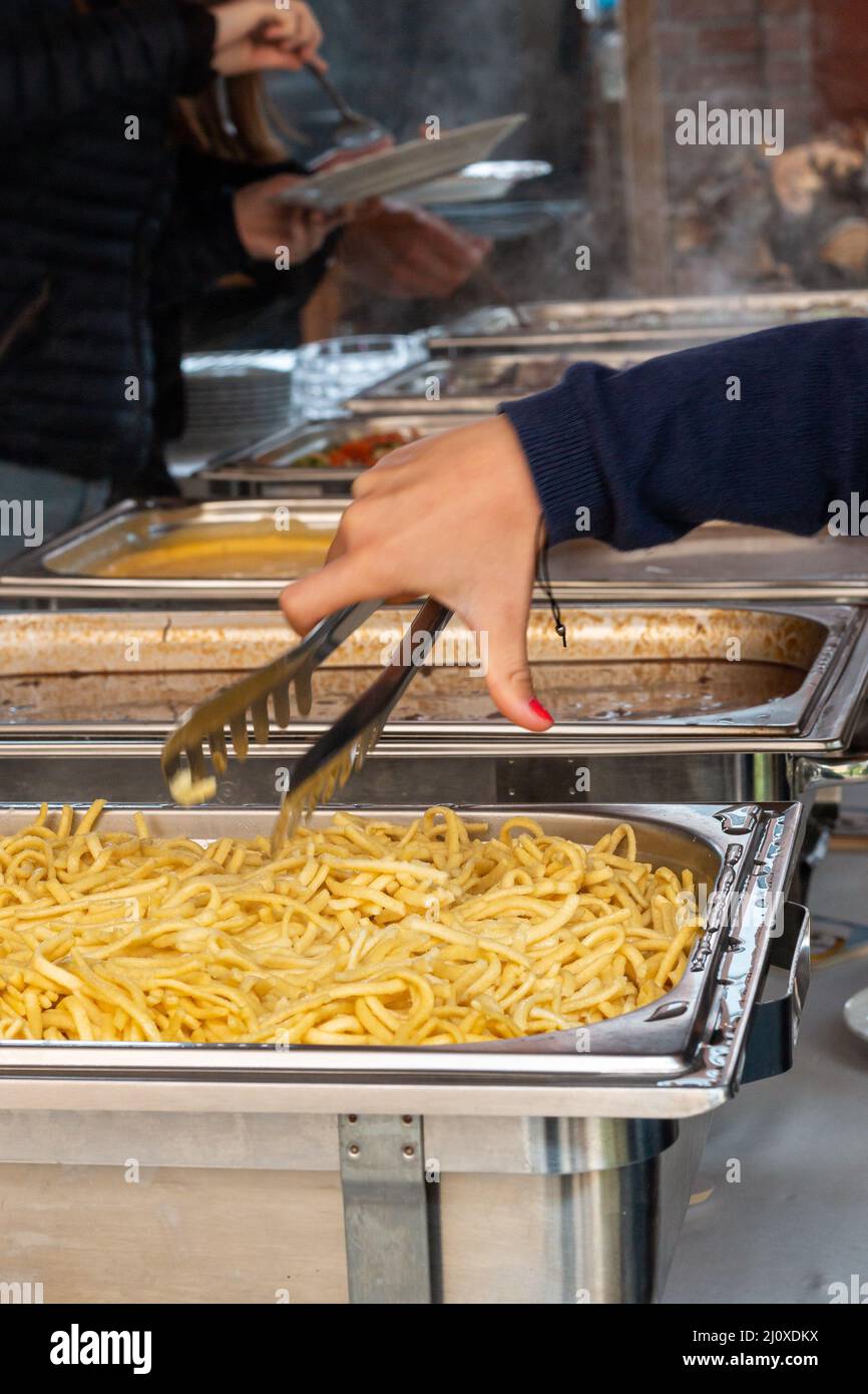 Female's hand grabbing noodles with pliers at a buffet Stock Photo - Alamy