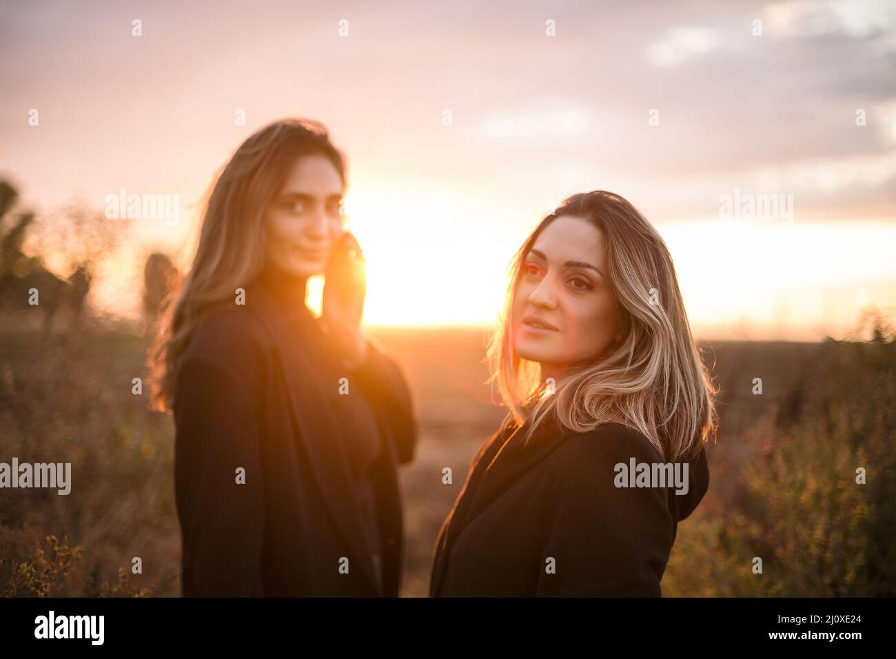 Two happy women girlfriends holding hands walking through autumn field ...