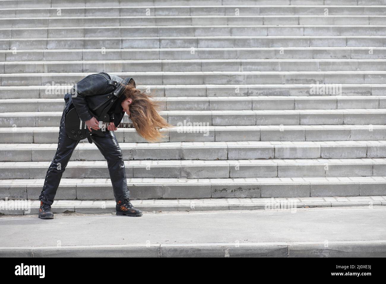 Rock guitarist on the steps. A musician with a bass guitar in a leather ...