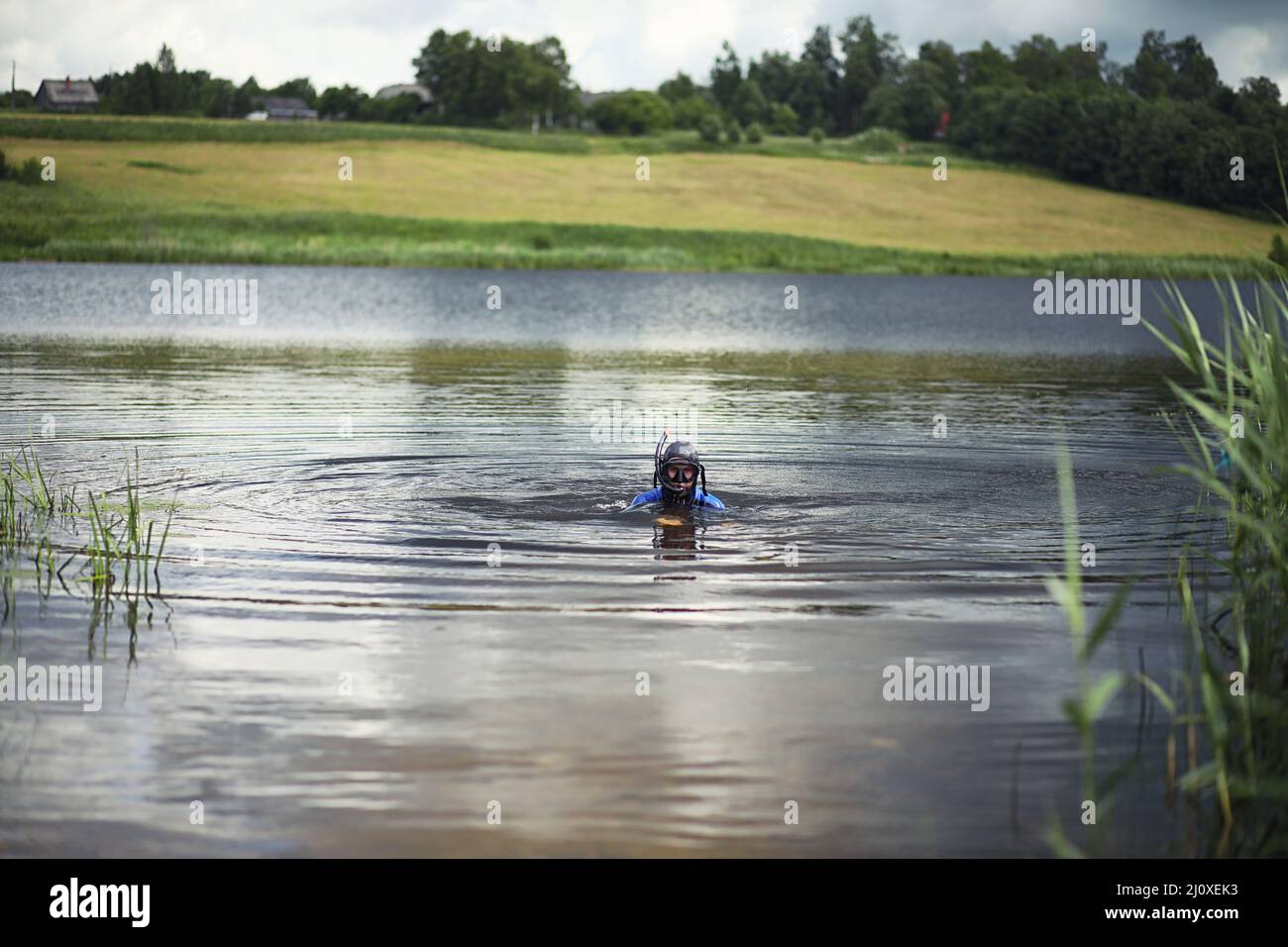 A scuba diver in a wet suit prepares to immerse in a pond Stock Photo ...