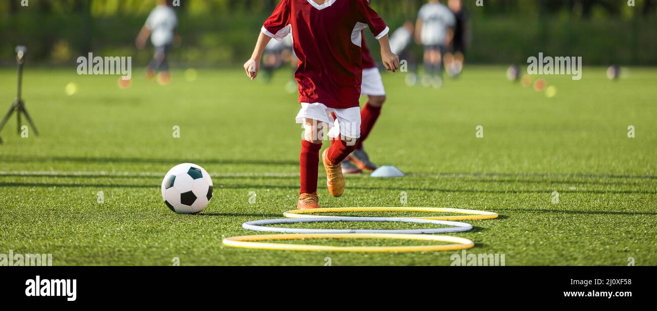Children on agility sports soccer training. Young boy jumping over hula ...