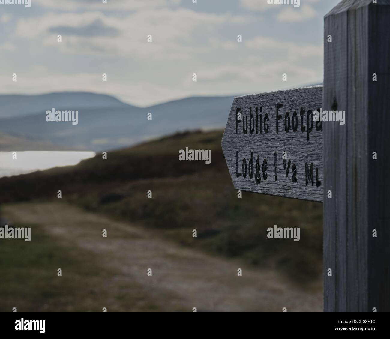 Wooden road sign with "Public Footpath Lodge 1.5 ML" written on it ...