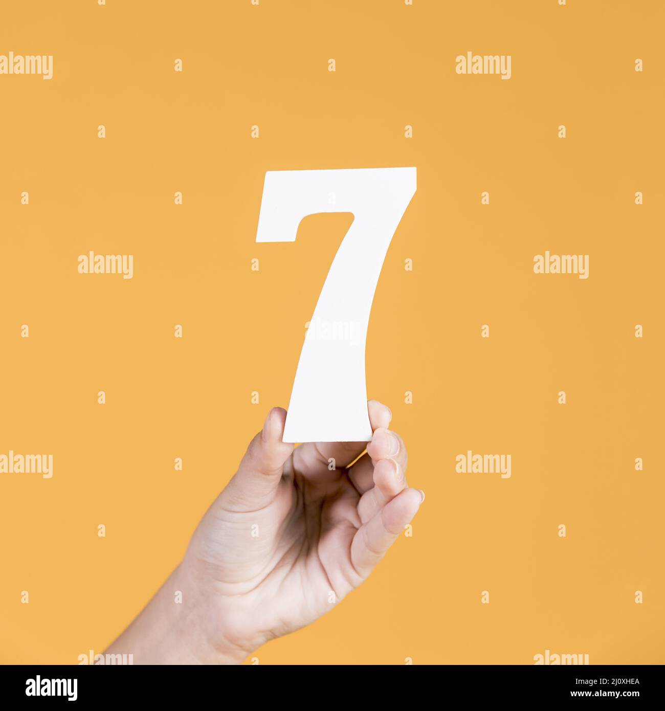 Human hand holding number seven against yellow background. High quality ...