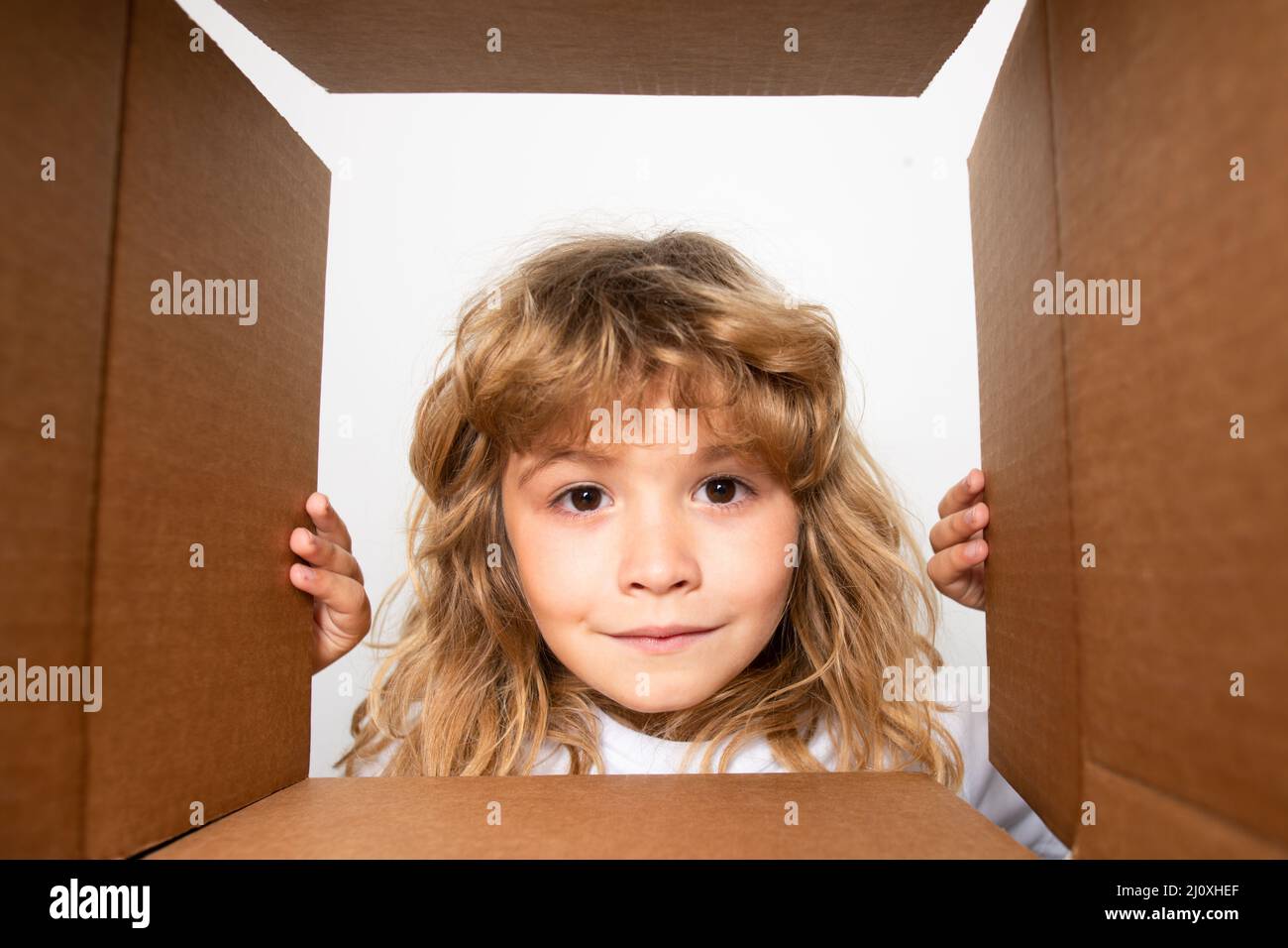 Excited child boy age 7 year looking into the box, shipping cardboard ...
