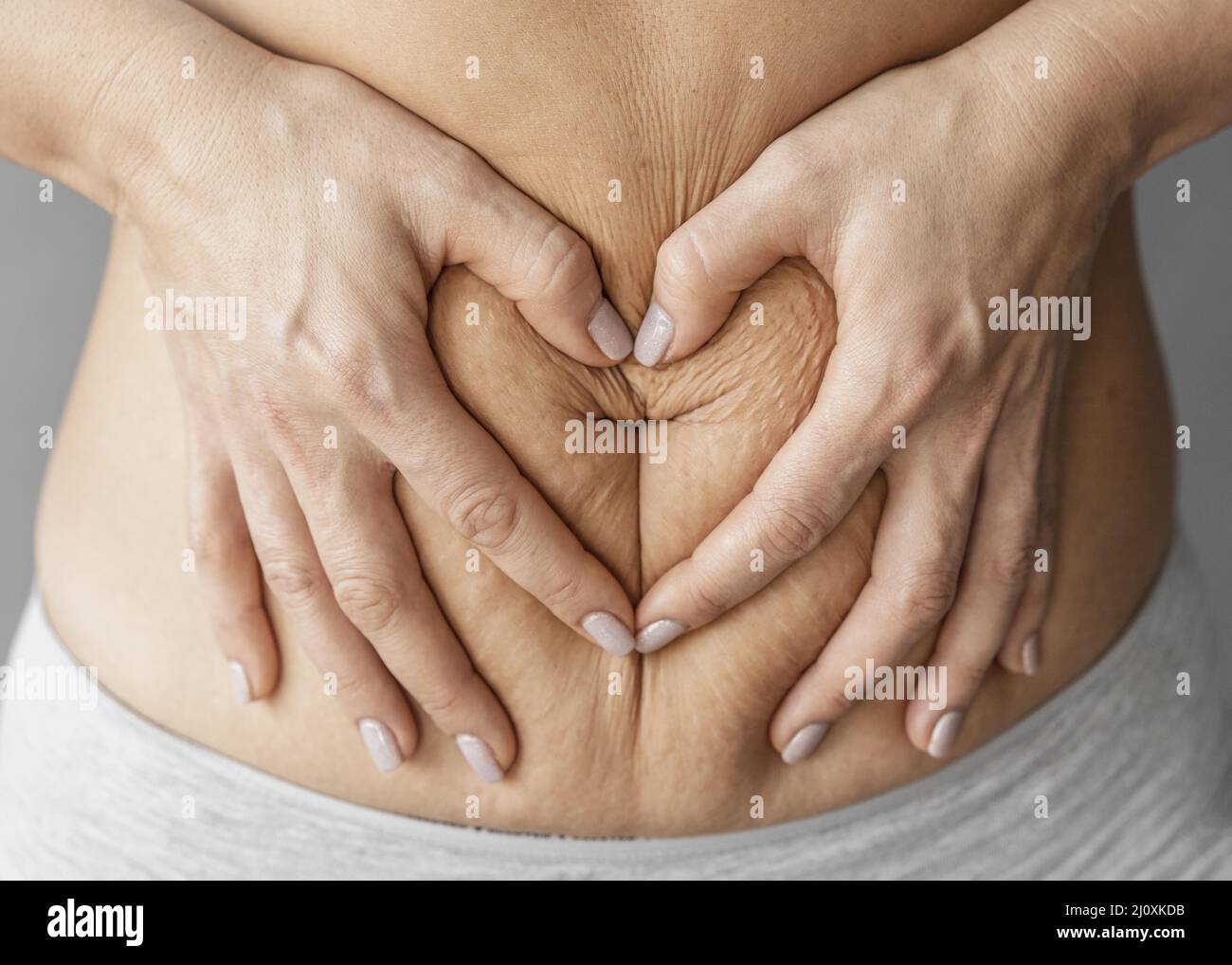 Close up hands holding belly Stock Photo - Alamy