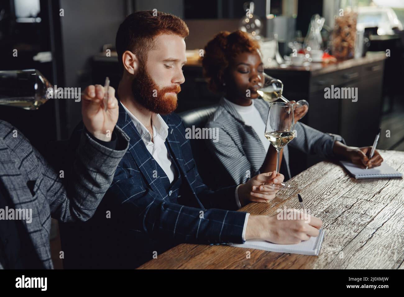 Sommeliers female and male tasting white wine and making notes at ...