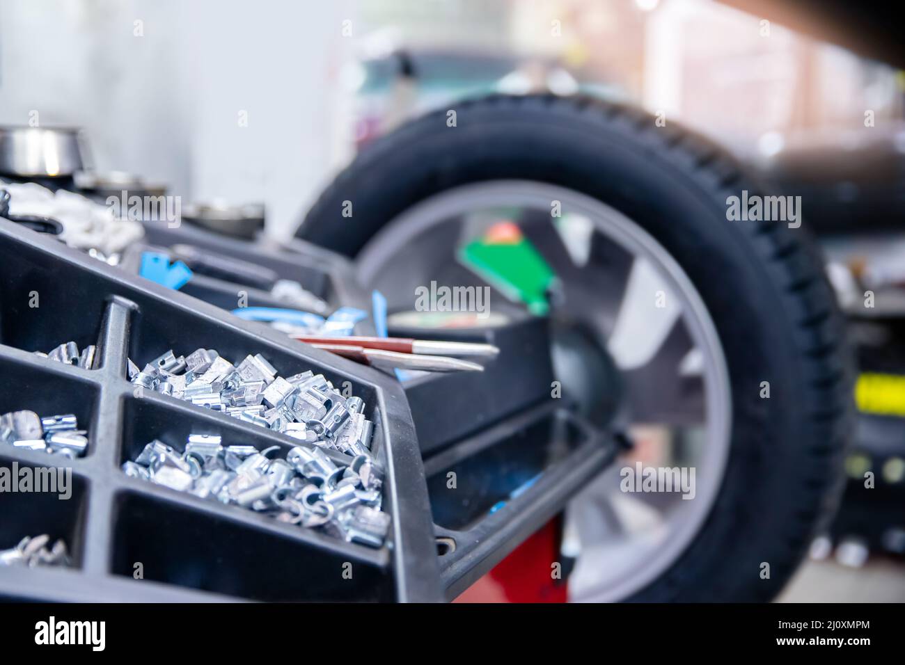 Concept balancing wheel in car service. Auto mechanic places weights on ...