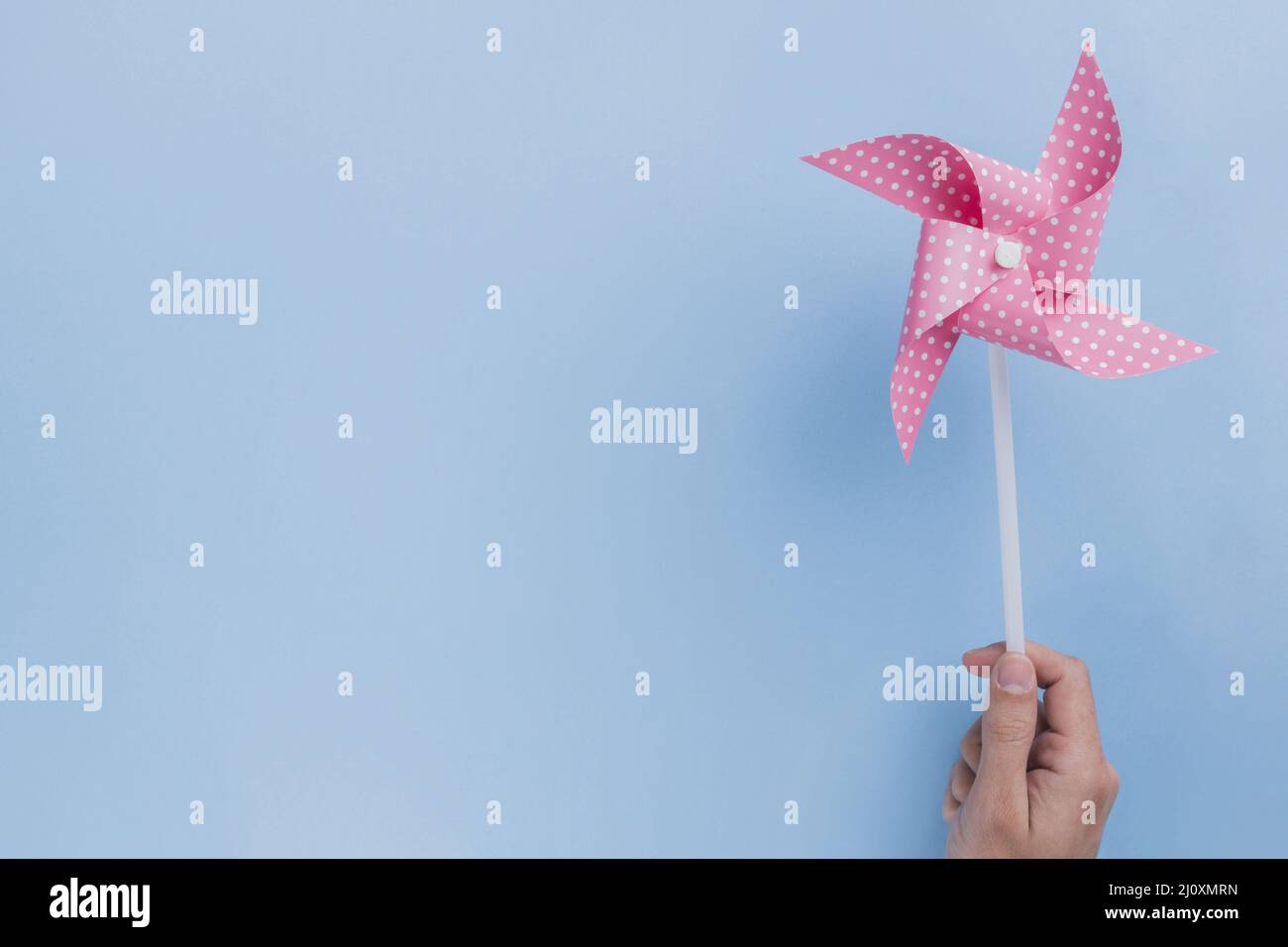 Close up human hand holding polka dotted pinwheel blue backdrop. High ...