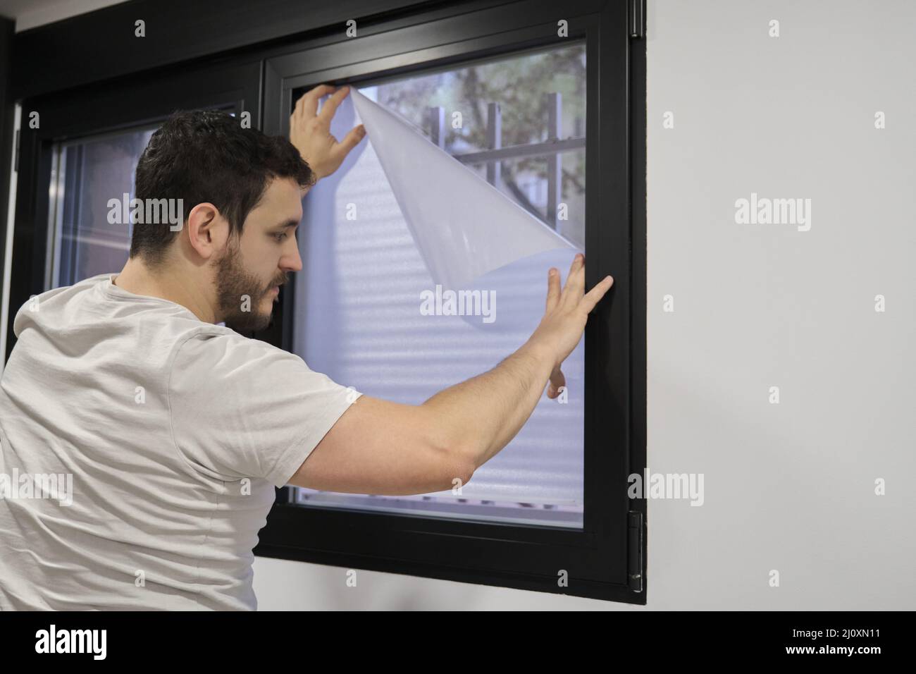 Man installing frosted window vinyl on window glass Stock Photo - Alamy