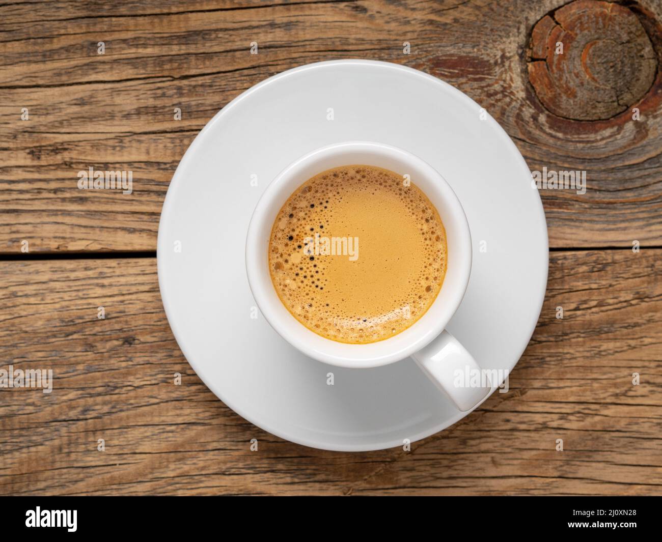 Black frothy coffee in white cup with saucer on aged wooden background ...