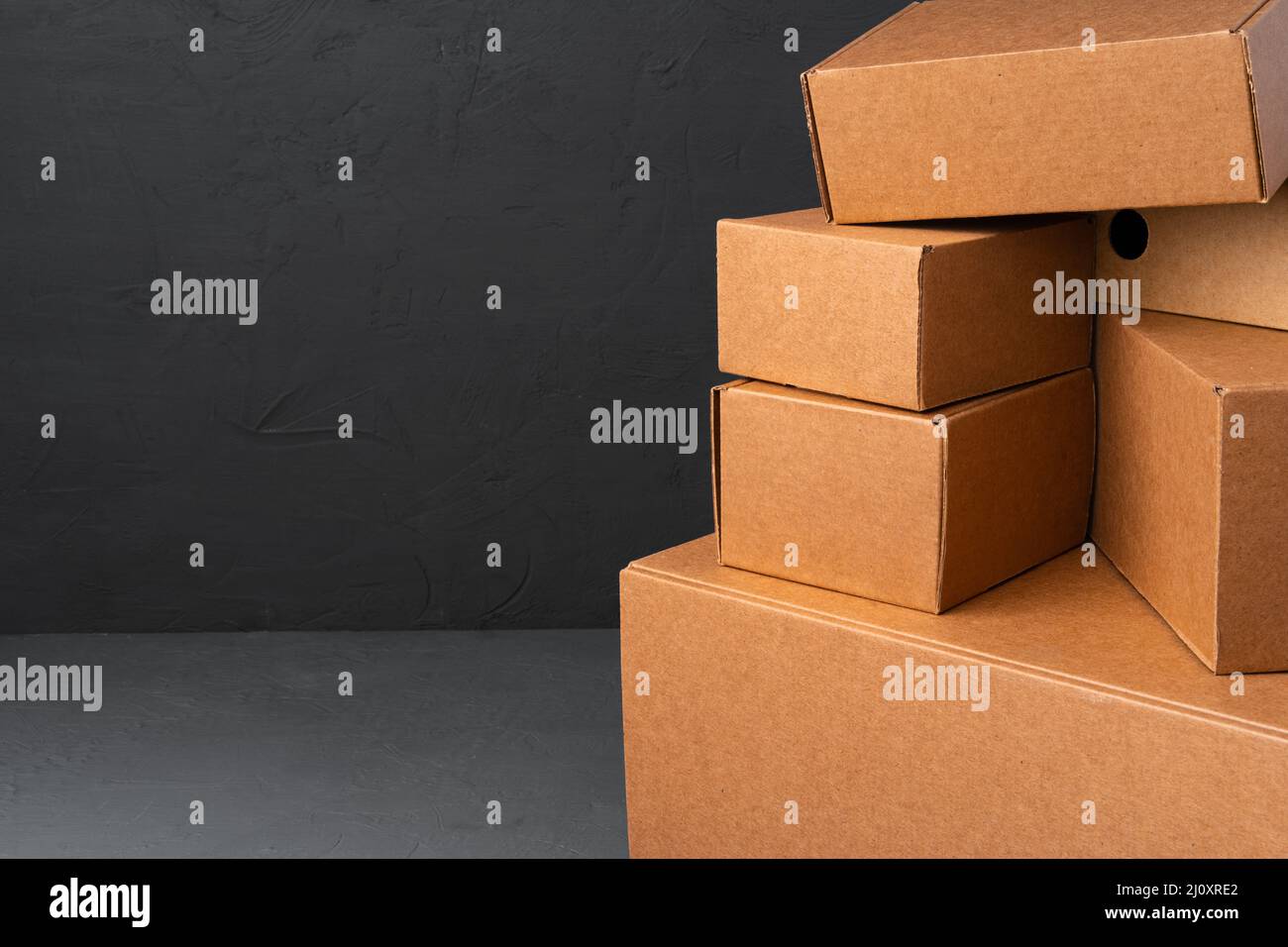 Stack of cardboard boxes against black background Stock Photo - Alamy