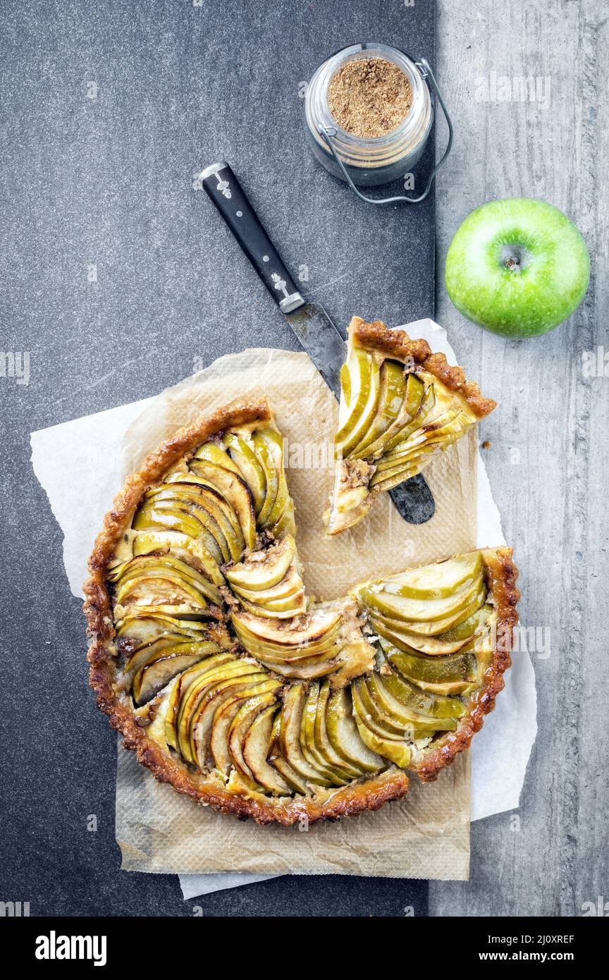 Traditional French apple cake offered as top view on a backing paper on ...