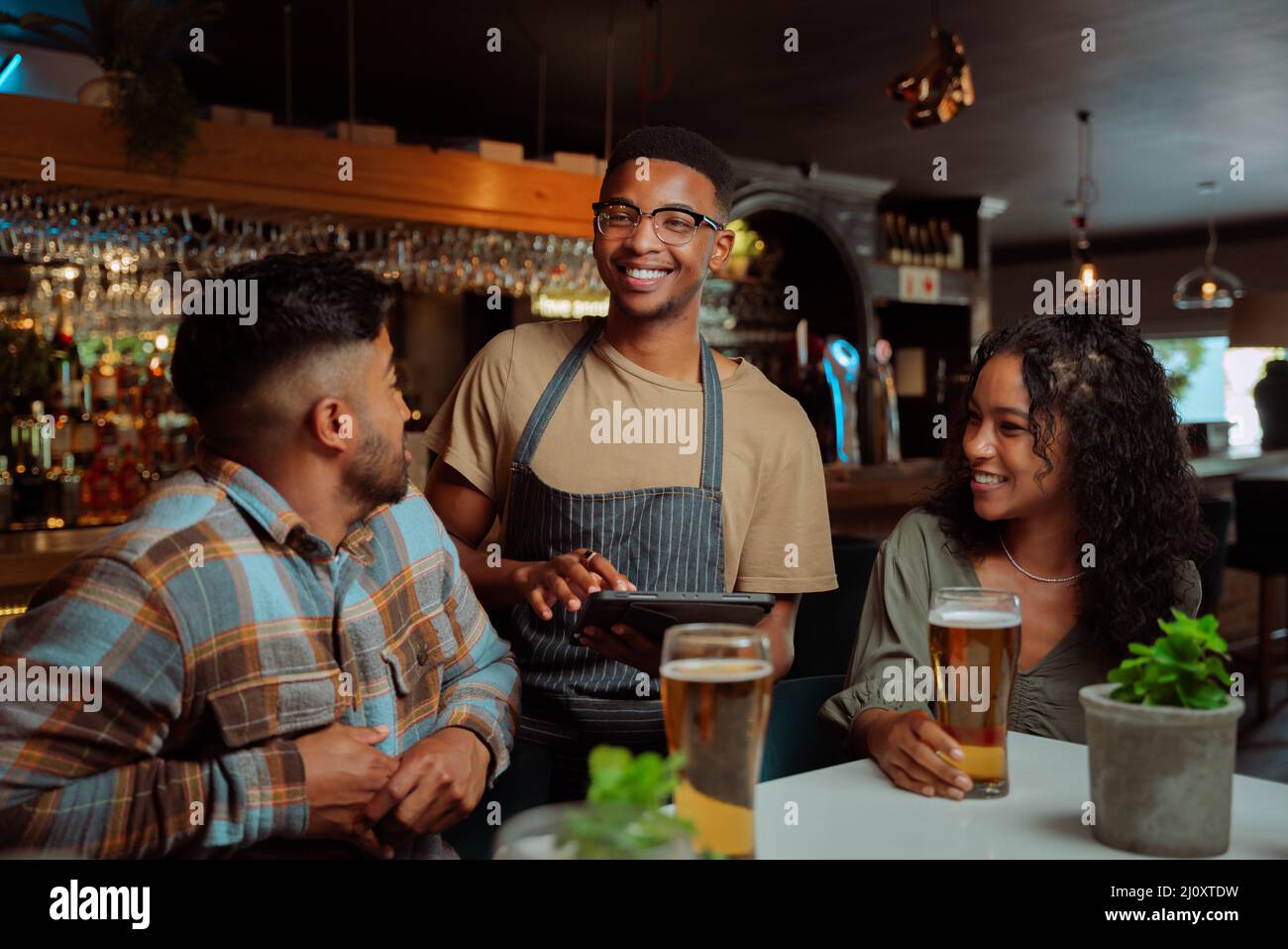 African American male waiter serving couple and friends at the ...