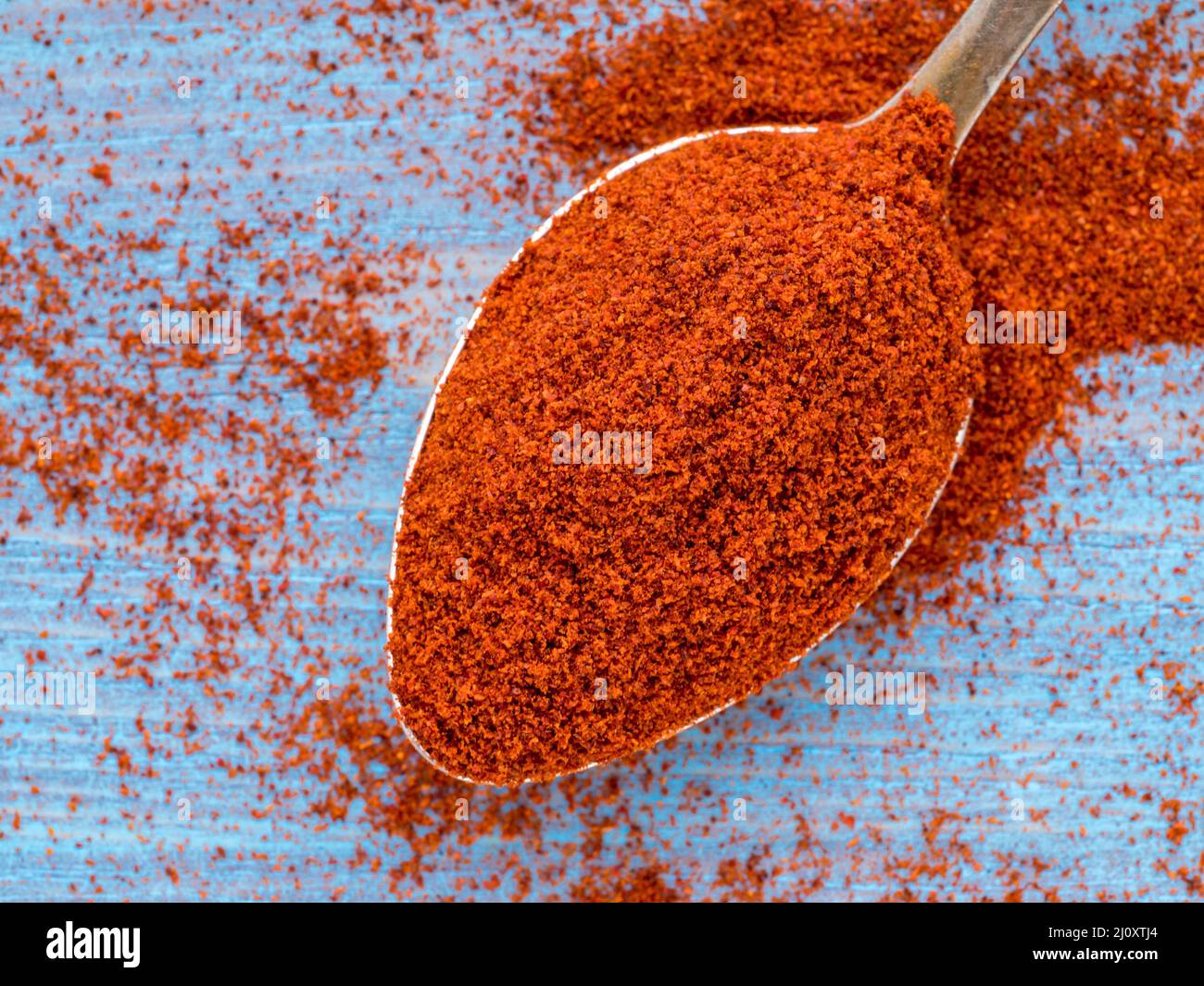 One heaping scoop of spices of paprika, powder scattered on the wooden ...