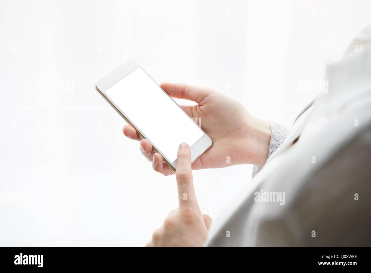 Unrecognizable woman is holding cell phone. View from behind, mockup ...