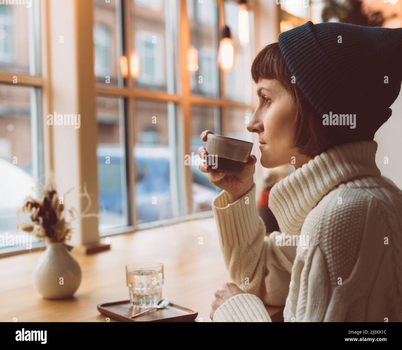 Beautiful female in cafe in Christmas winter holidays in lights of ...