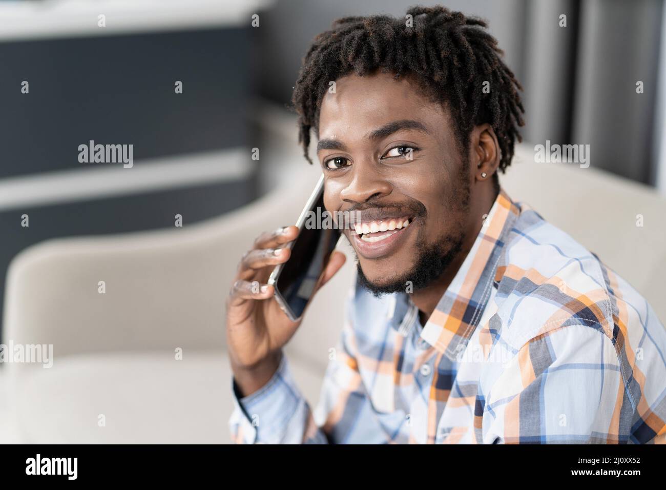 Young African American guy with phone in hand looking at camera while ...