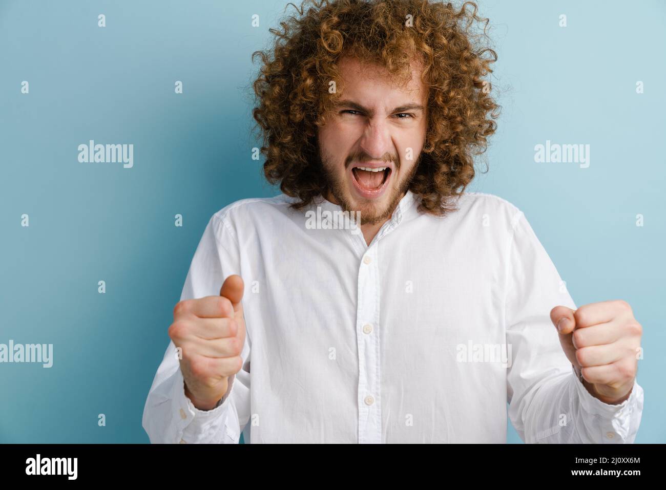 Young man with ginger curly hair gesturing and screaming at camera ...
