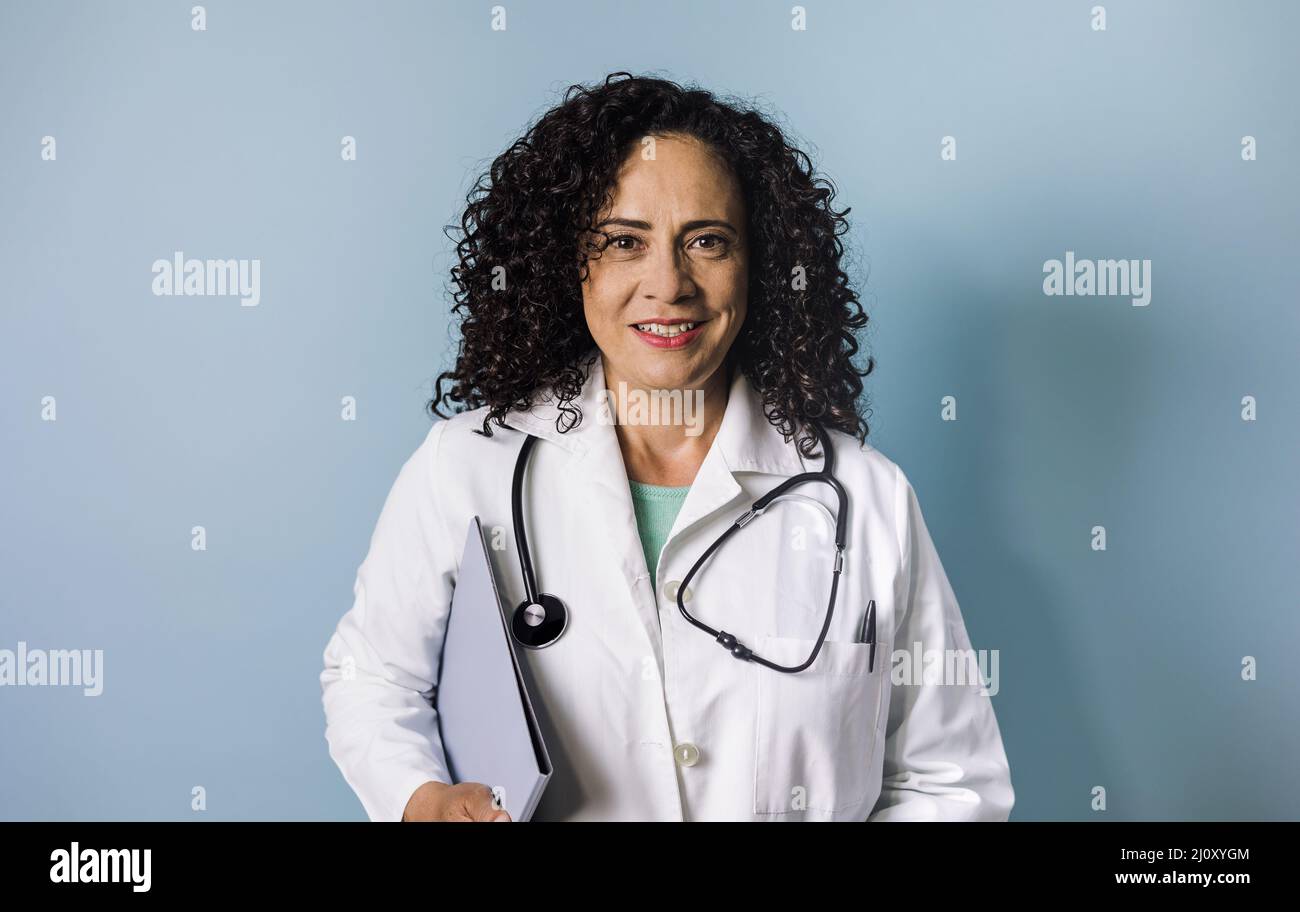 hispanic doctor woman portrait with copy space over blue background ...