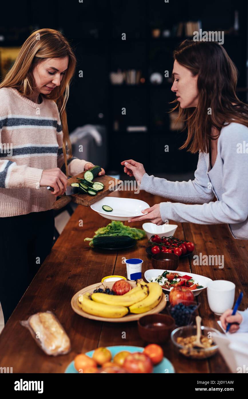 Two young women are cooking a meal Stock Photo - Alamy