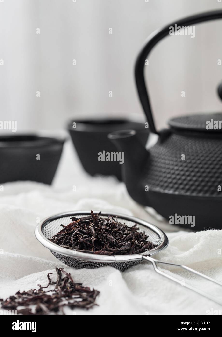 Strainer infuser with loose black tea on light cloth with iron teapot ...