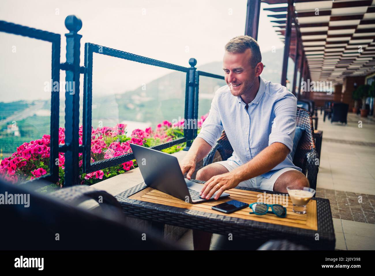 A successful male businessman is sitting at a table with a laptop, he ...