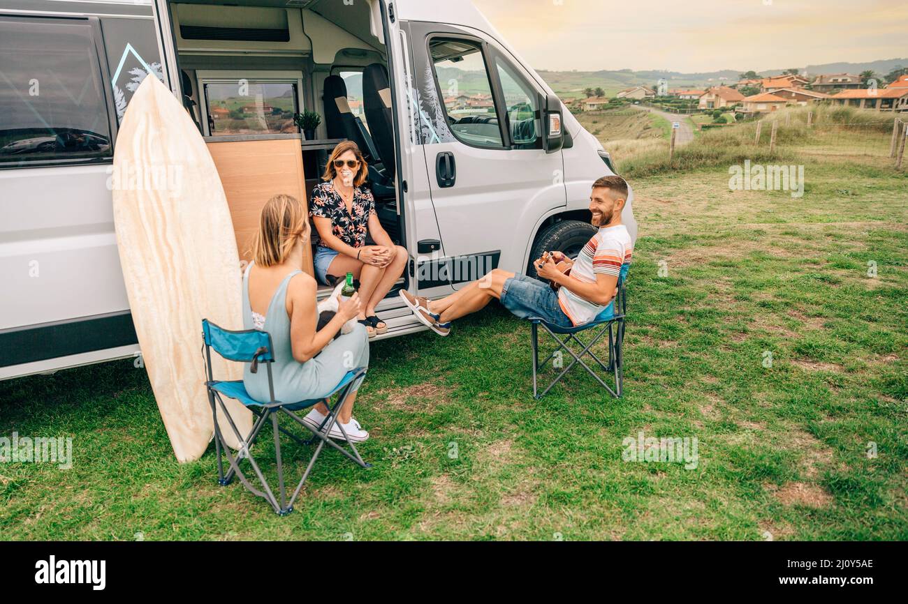 Friends with their dog talking and drinking beer in front of their ...