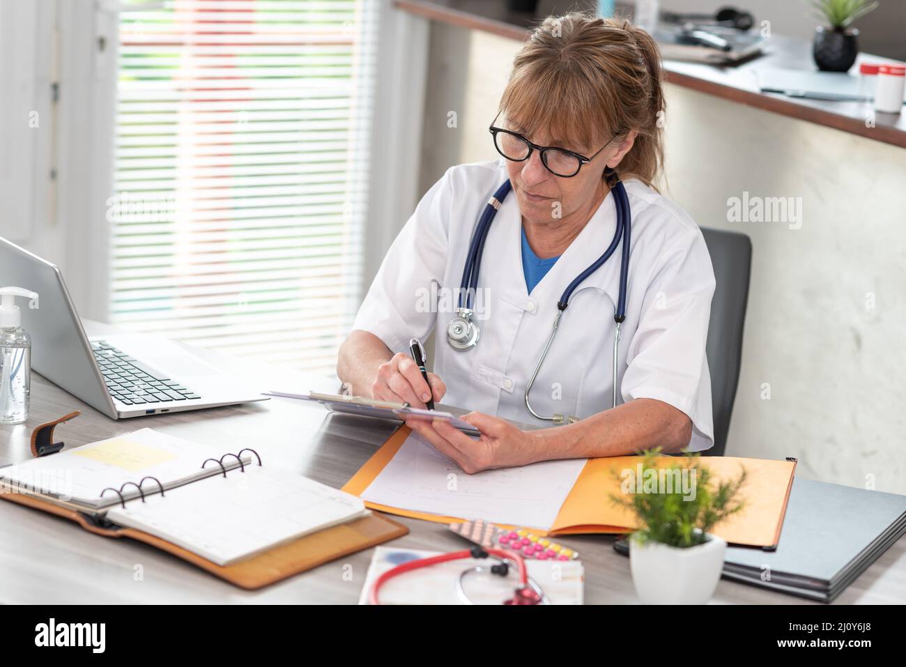 Female doctor taking notes on clipboard in medical office Stock Photo ...
