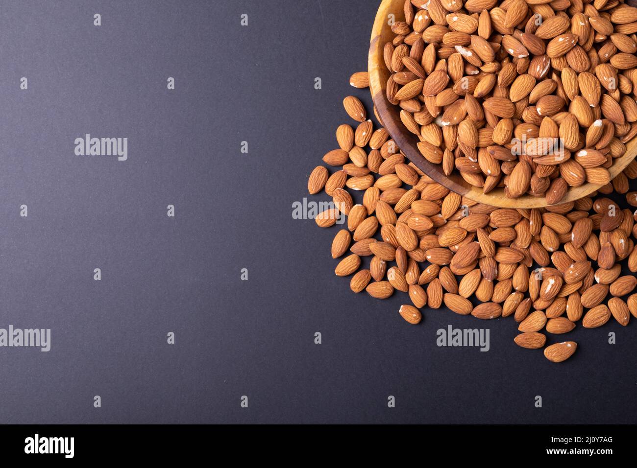 Overhead view of nutritious almonds in wooden container on black ...