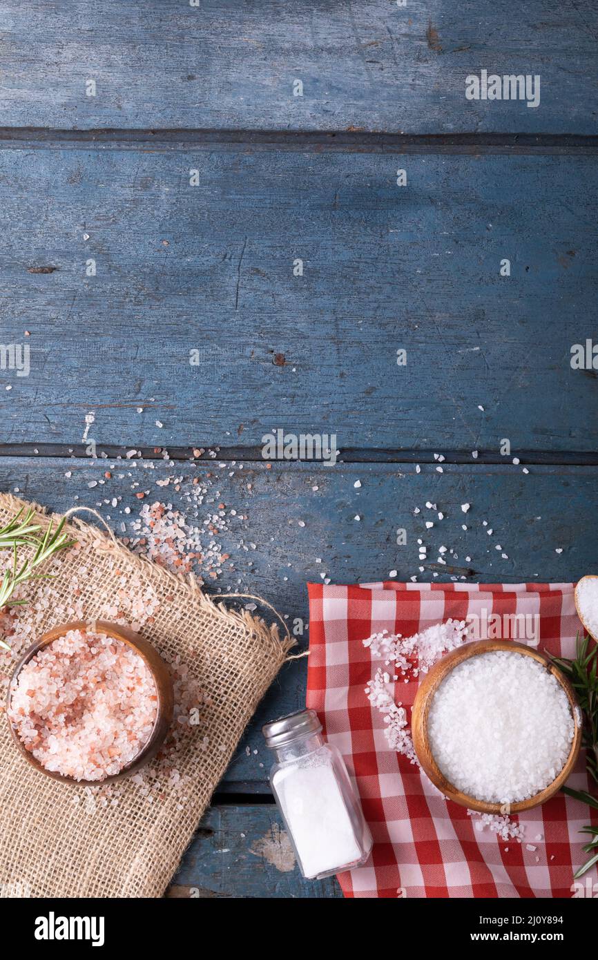 Pink and white rock salt in bowls by salt shaker on fabric at wooden ...