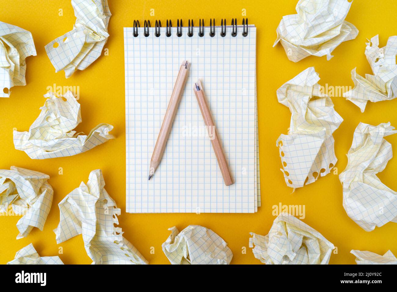 Red pencil and notebook on a yellow background. Crumpled sheets of ...