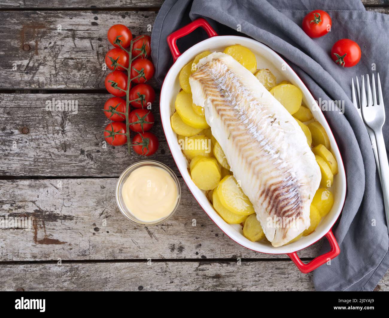 Fish cod baked in the oven with potatoes. Dark old wooden rustic gray ...