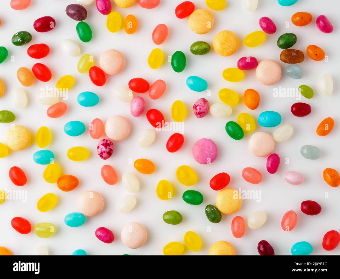 Many scattered colorful sweets, candies, lollipops on white background ...